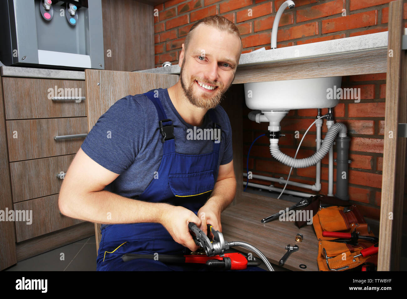 Handsome smiling plumber at the kitchen hi-res stock photography and ...