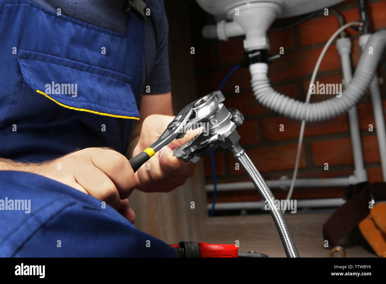 Hands of plumber connecting pipe union to flexible hose, close up view ...