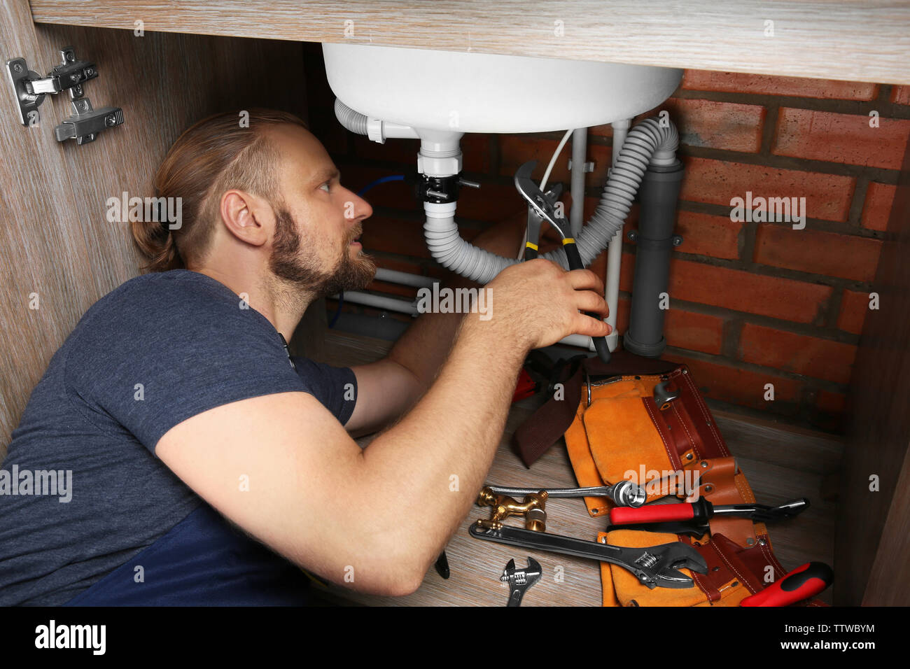 Handsome plumber repairing sink pipes in kitchen Stock Photo - Alamy