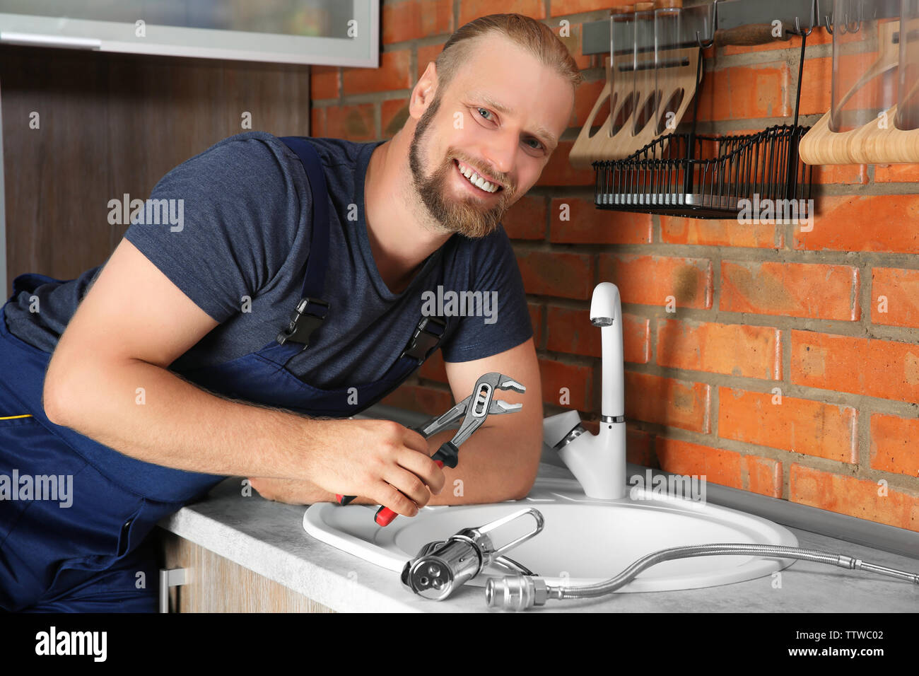 Handsome smiling plumber at the kitchen hi-res stock photography and ...