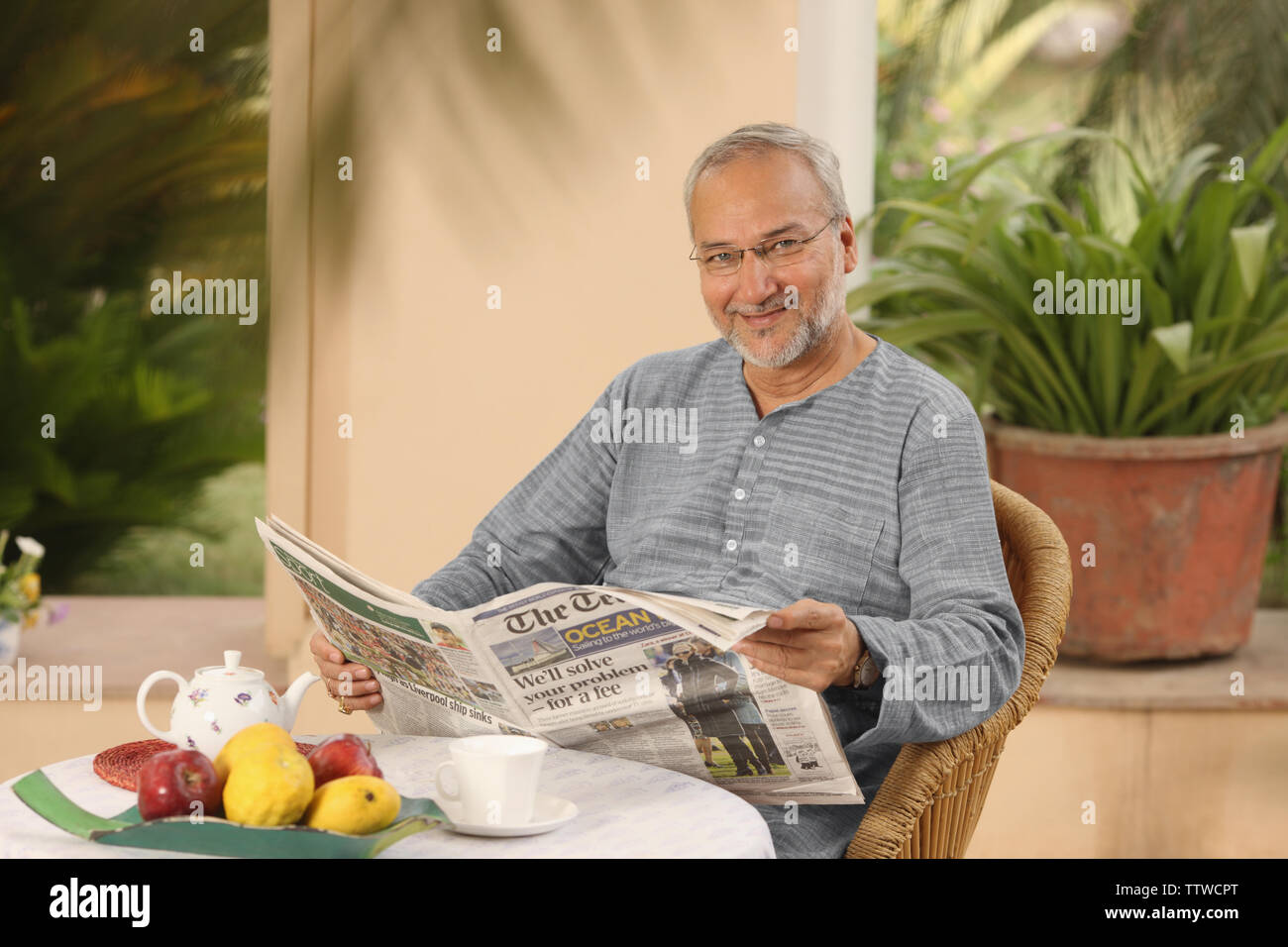 Man reading a newspaper at a breakfast table Stock Photo - Alamy