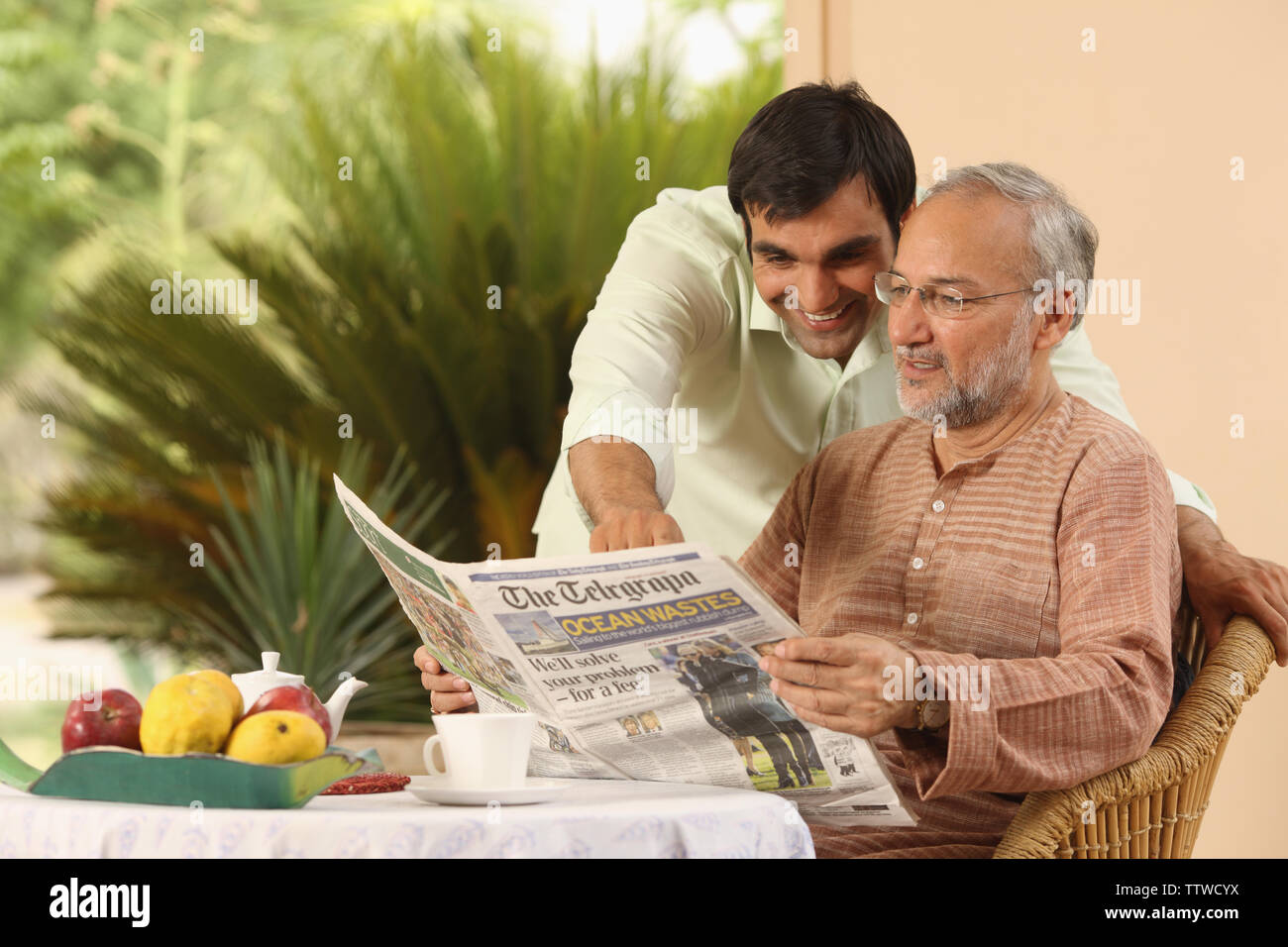 Man with his father looking at a newspaper Stock Photo - Alamy