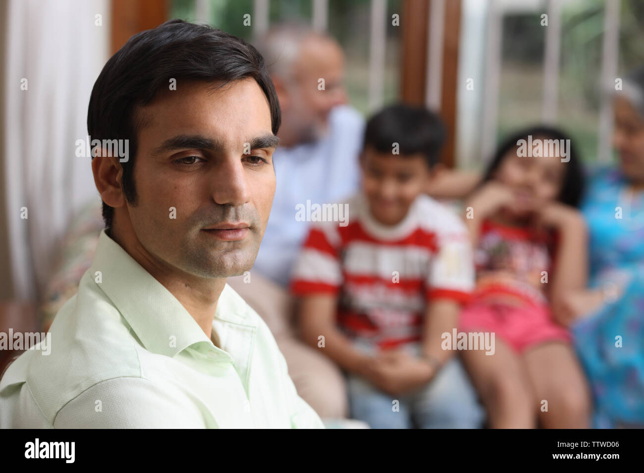 Man thinking with family in the background Stock Photo - Alamy