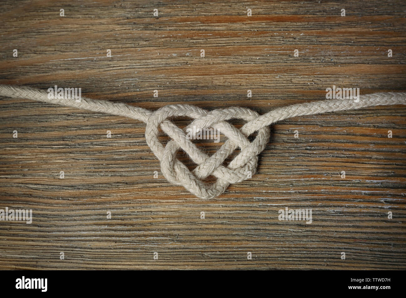 Heart shaped knot on wooden background Stock Photo - Alamy