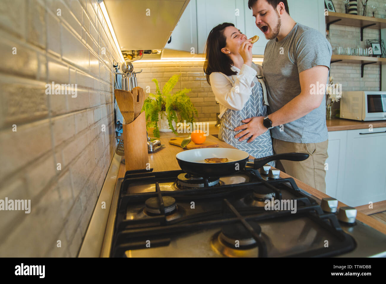 lovely couple hugging on the kitchen while cooking breakfast. domestic ...
