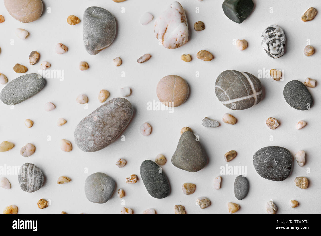 Scattering of big and small pebbles on white background Stock Photo - Alamy