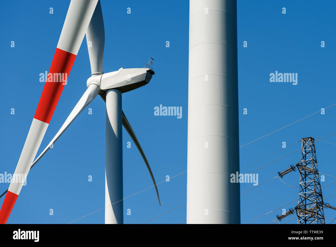 White and red wind turbines and high voltage tower (power line) on a ...