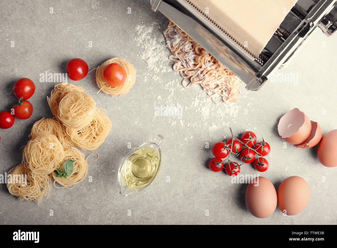 Products, spaghetti and pasta machine on kitchen table Stock Photo - Alamy