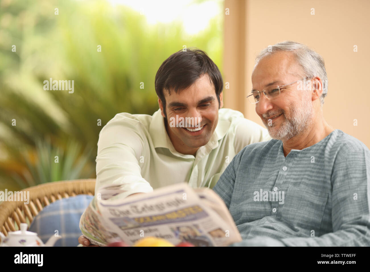 Man with his father looking at a newspaper Stock Photo - Alamy