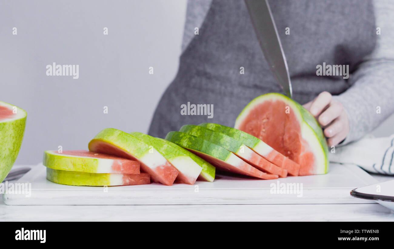 Slicing red watermelon into small pieces on a white cutting board Stock ...