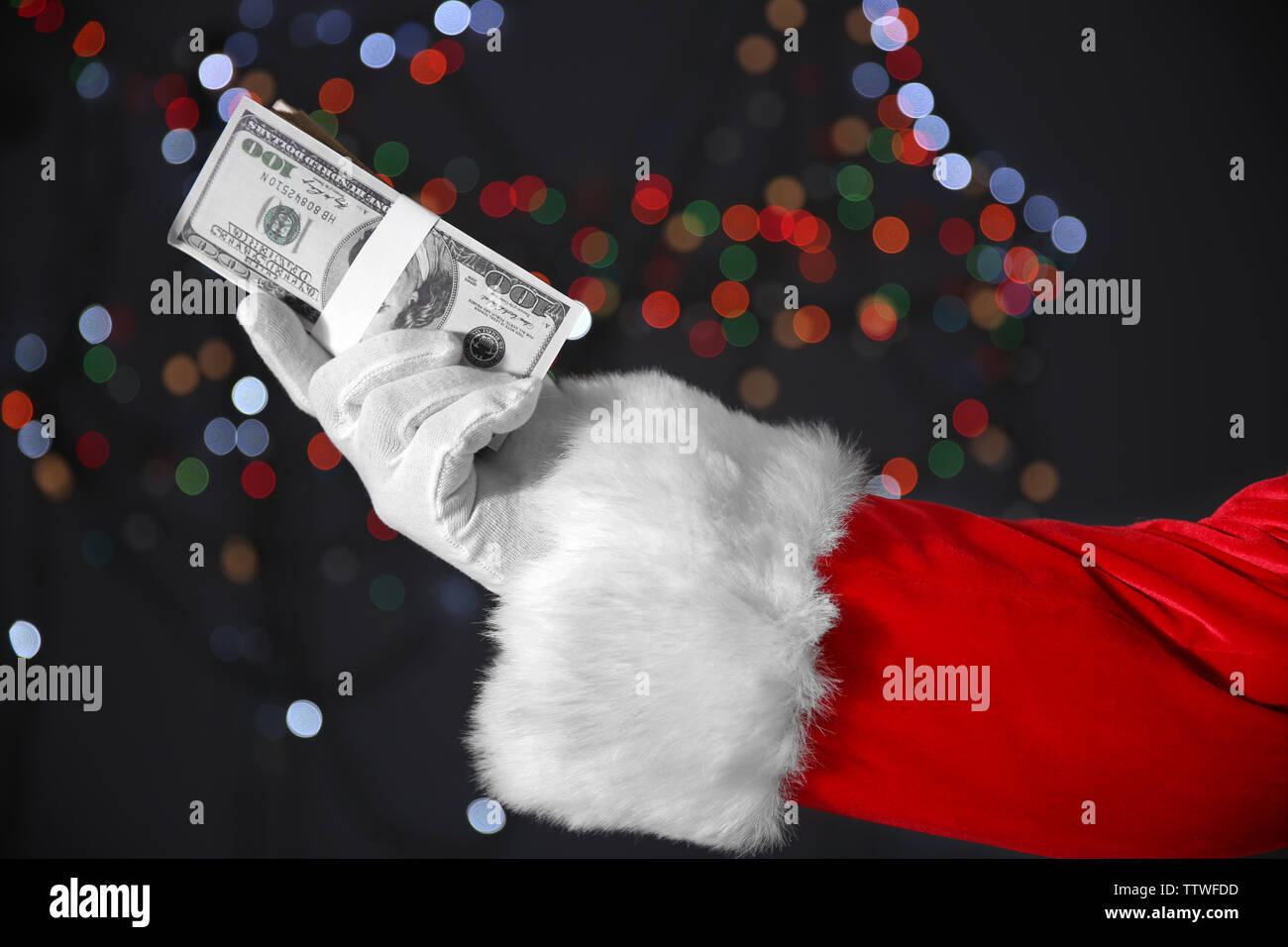 Santa Claus hand holding money on blurred lights background Stock Photo ...