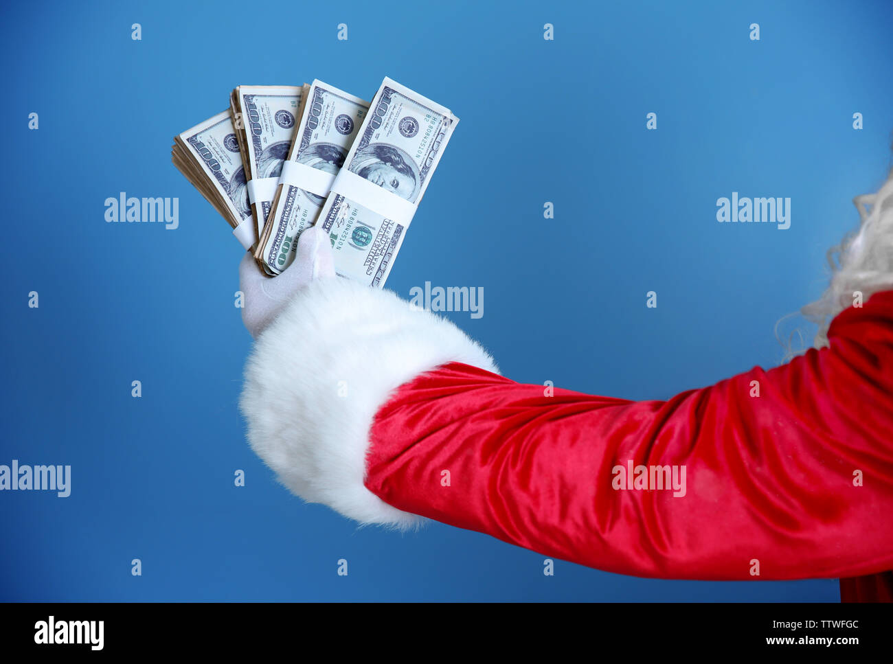 Santa Claus hand holding money on blue background Stock Photo - Alamy