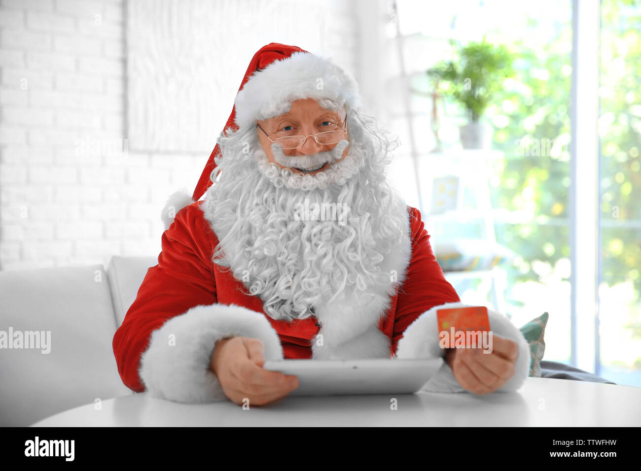 Santa Claus with credit card and tablet at home Stock Photo - Alamy