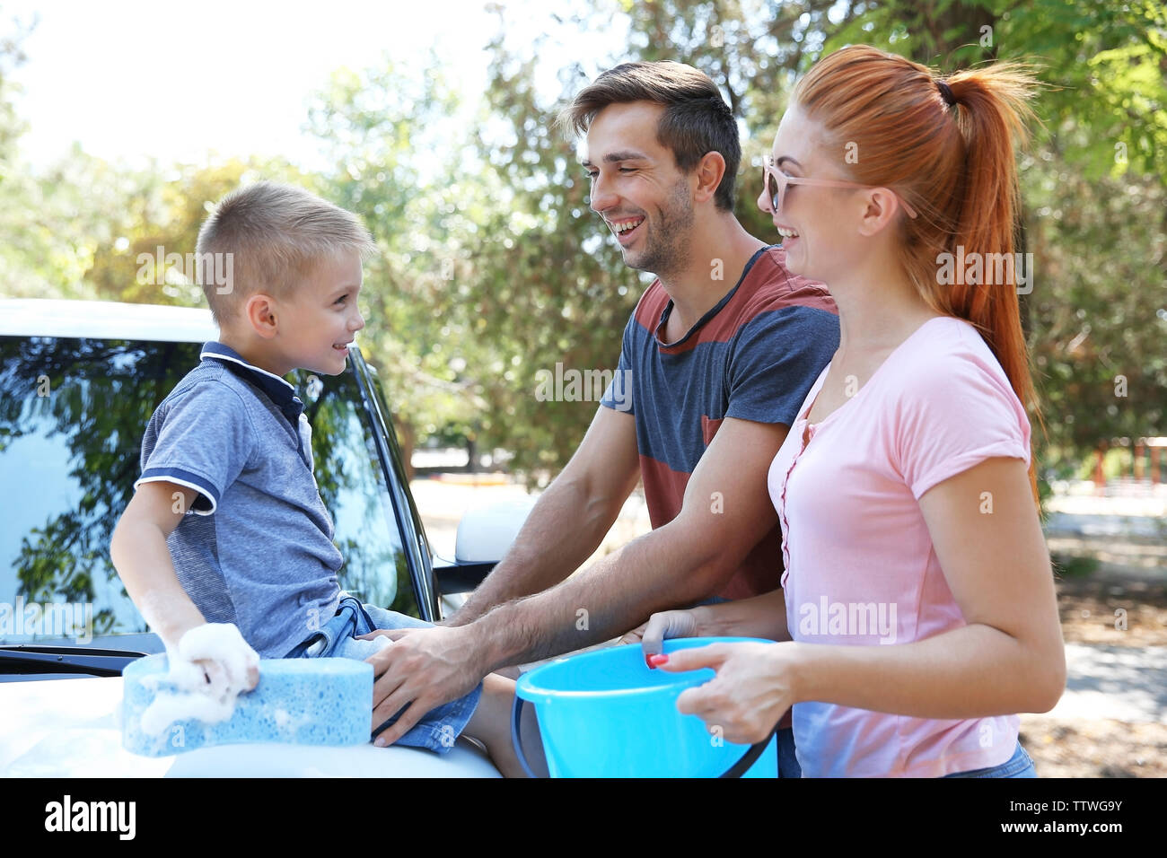 Happy family washing car on street Stock Photo - Alamy