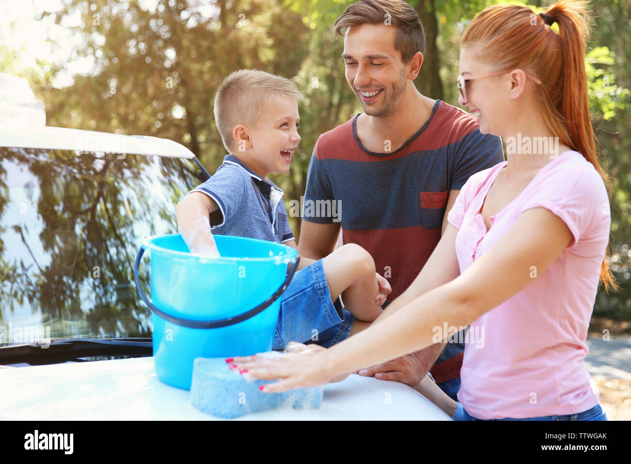 Happy family washing car on street Stock Photo - Alamy