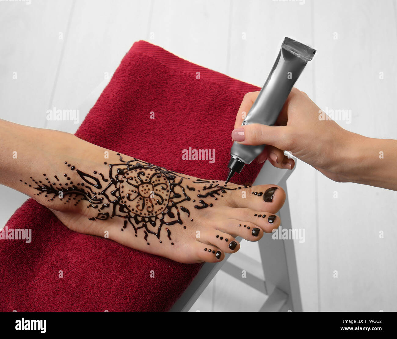 Woman applying henna on female foot Stock Photo - Alamy