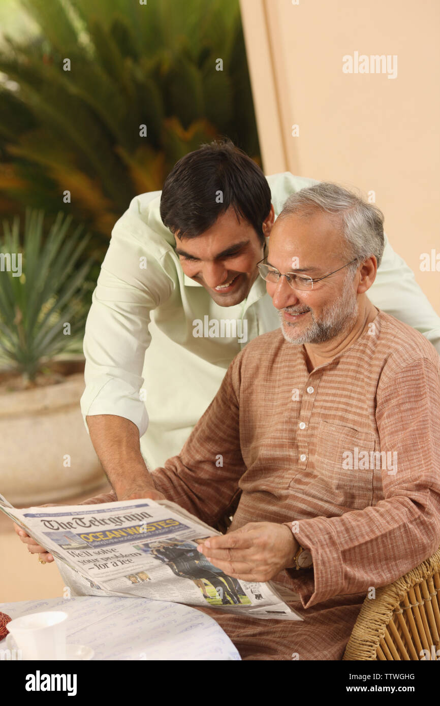 Man with his father looking at a newspaper Stock Photo - Alamy