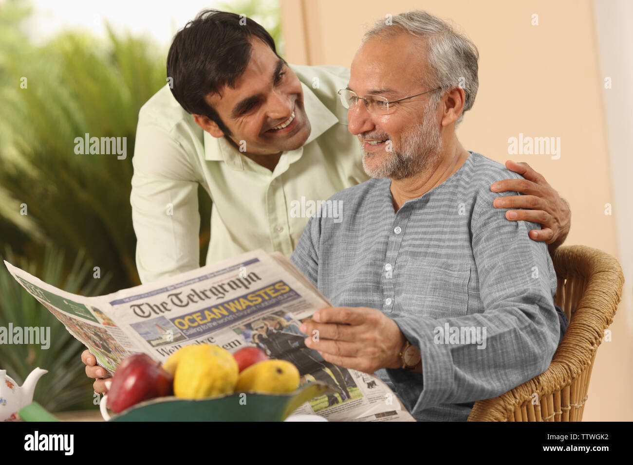 Man with his father looking at a newspaper Stock Photo - Alamy