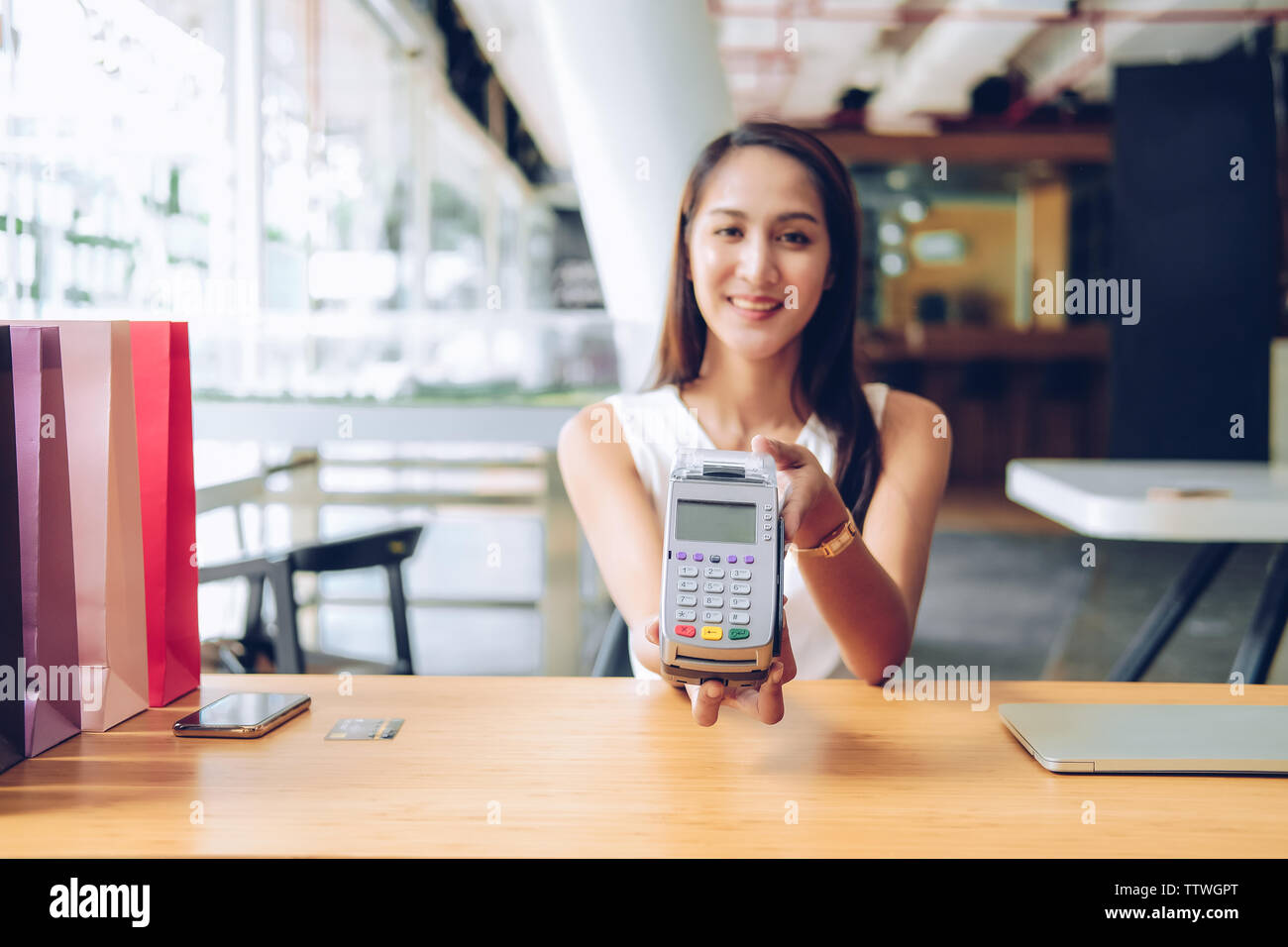 woman with credit card swiping machine & shopping bags on table ...