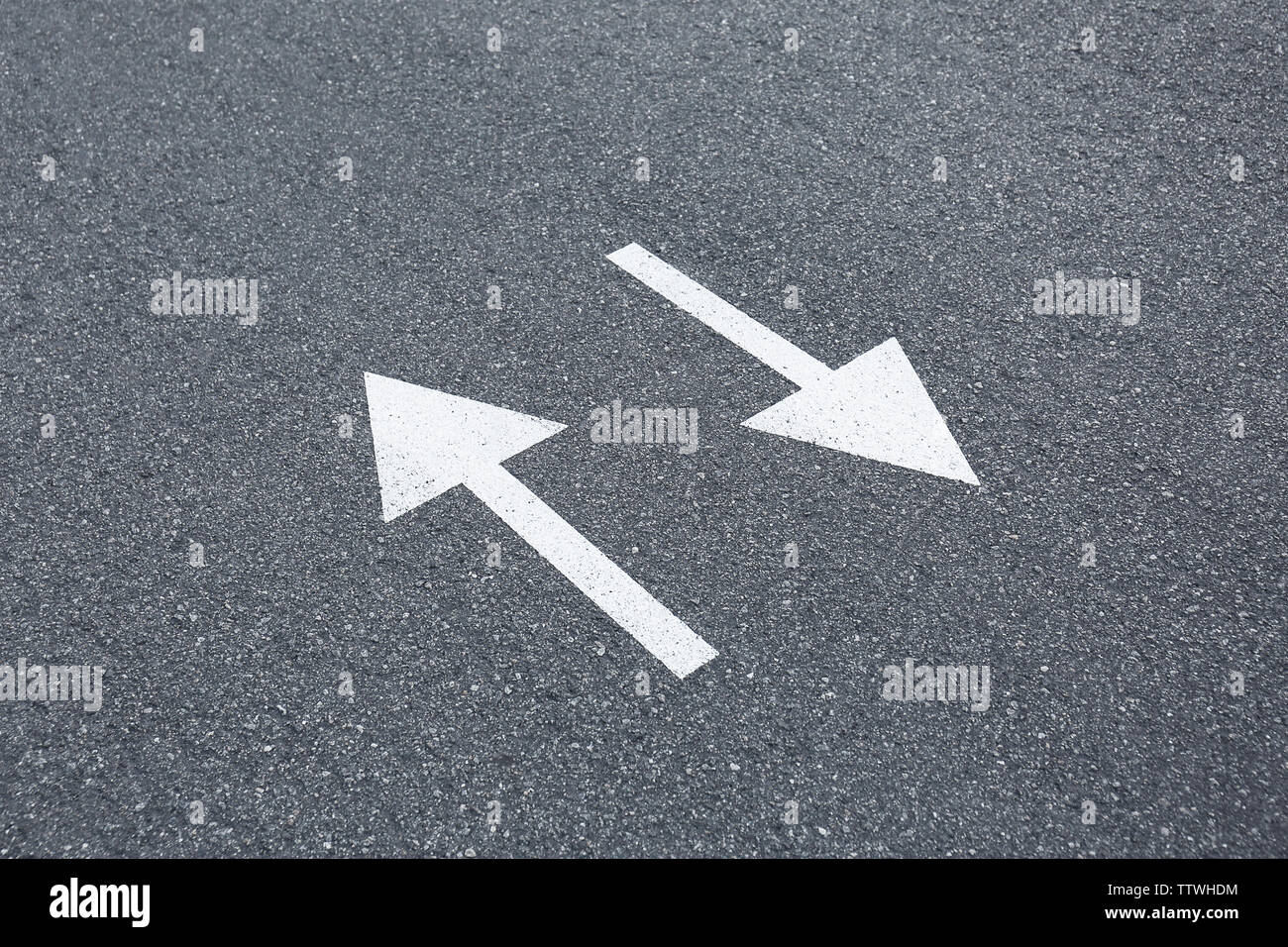 Arrow signs on asphalt road showing direction of movement, close up ...