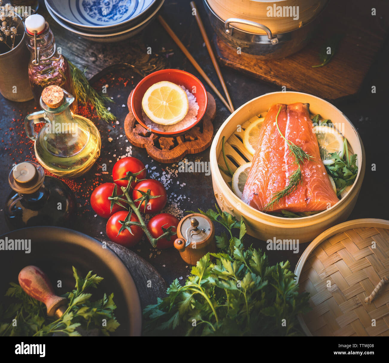 Preparation of salmon fillet on dark rustic kitchen table with ...