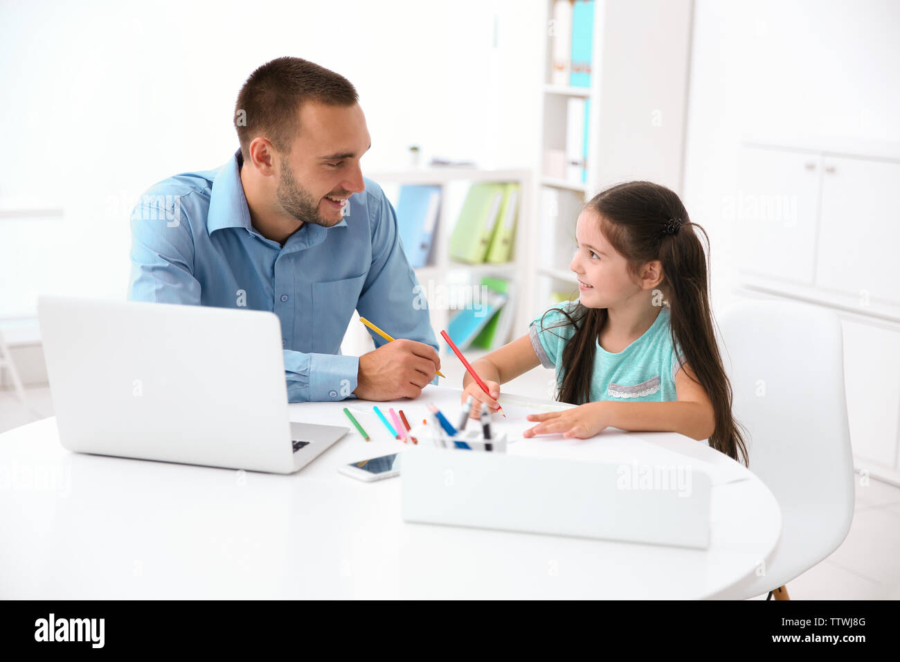 Daughter helping father working in office Stock Photo - Alamy