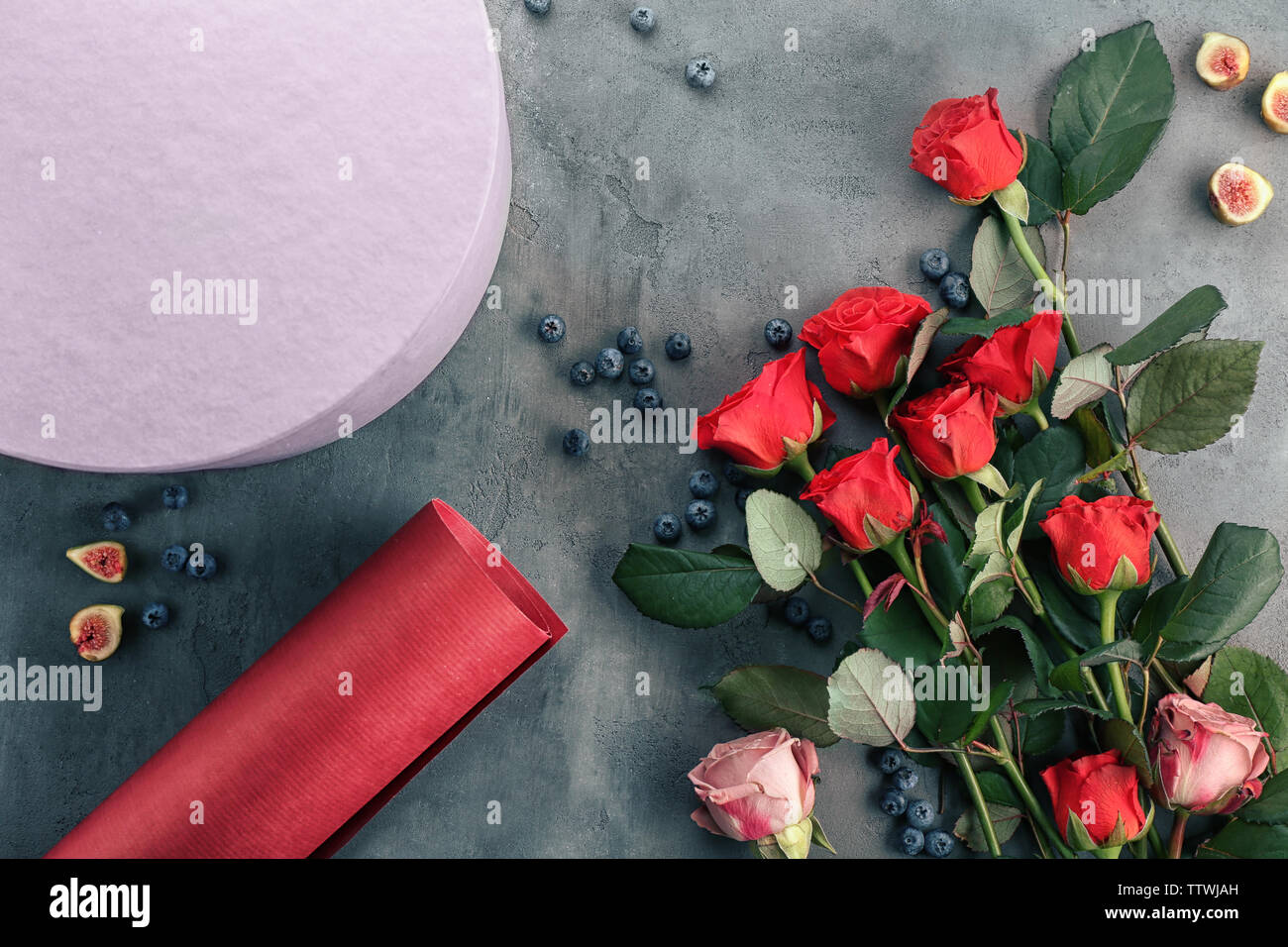 Beautiful red roses, carton box and wrapping paper on grunge textured ...