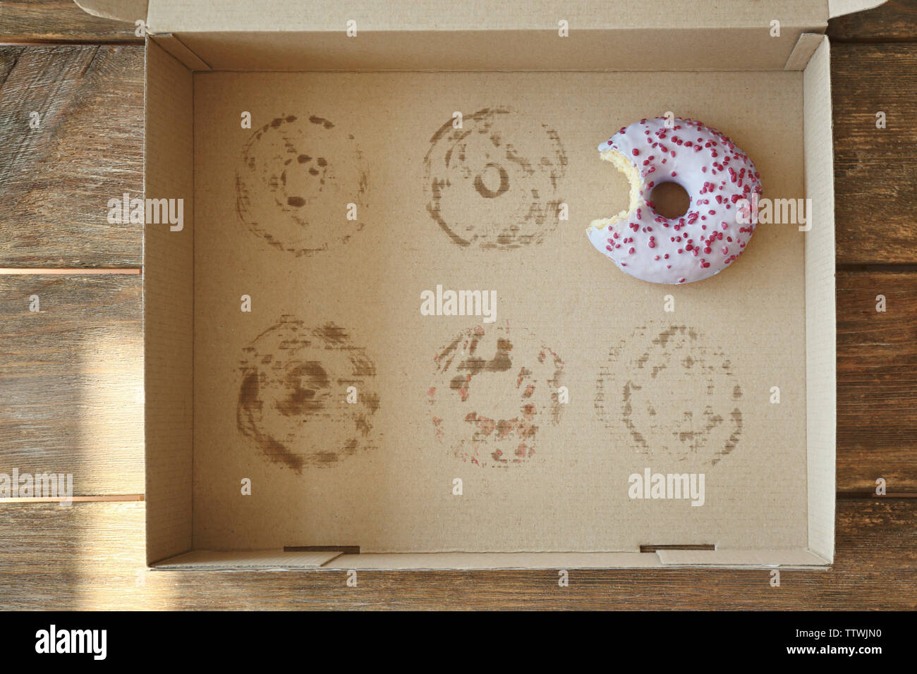 Donut with bite taken out lying in carton box Stock Photo - Alamy