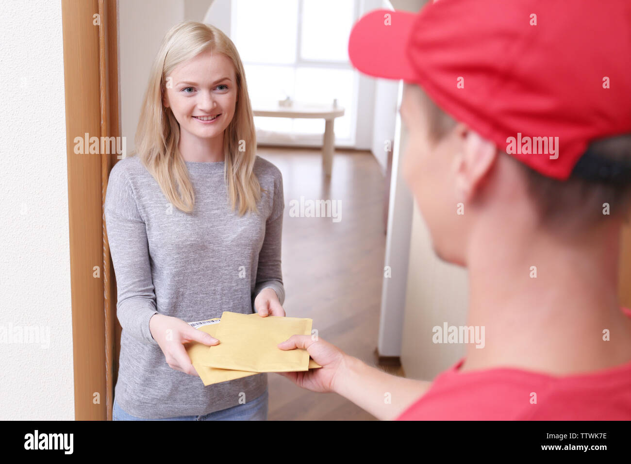 Young woman receiving package from courier Stock Photo - Alamy