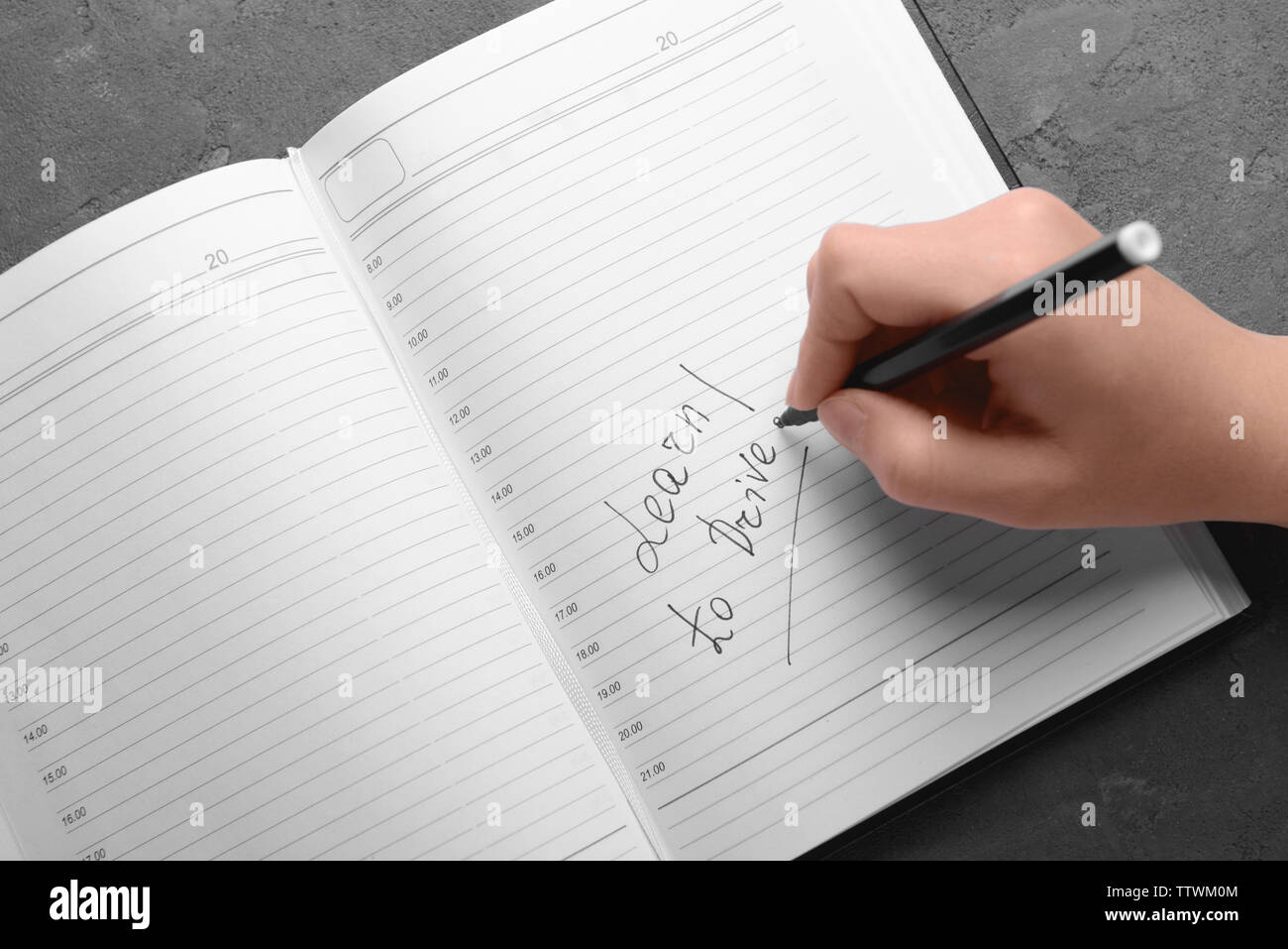 Woman writing on notebook reminder. Learn to drive concept Stock Photo ...