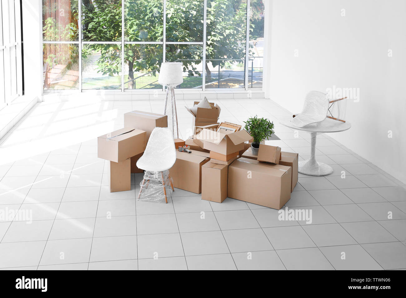 House moving concept. Boxes with furniture in new room with big window ...