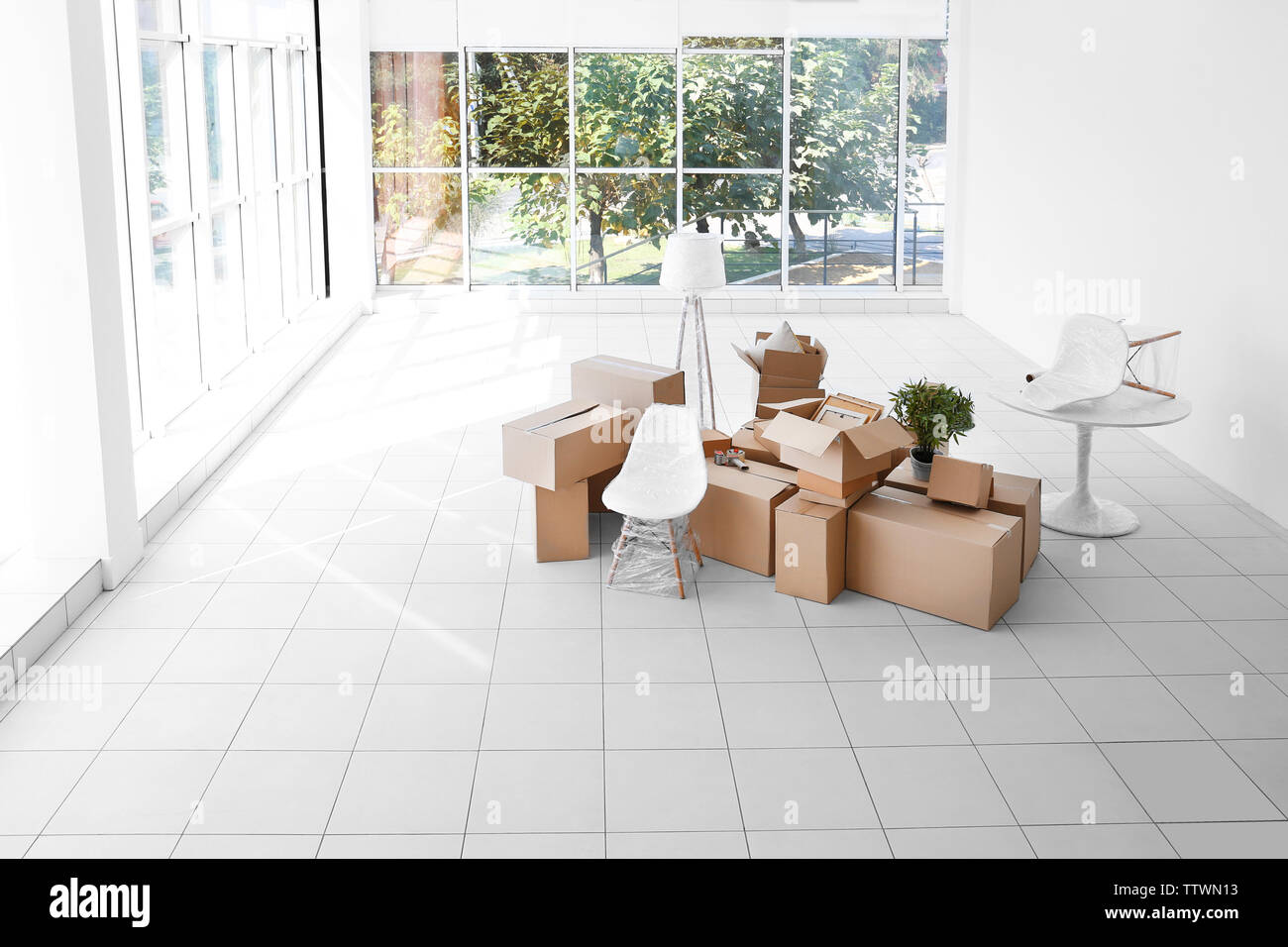 House moving concept. Boxes with furniture in new room with big window ...