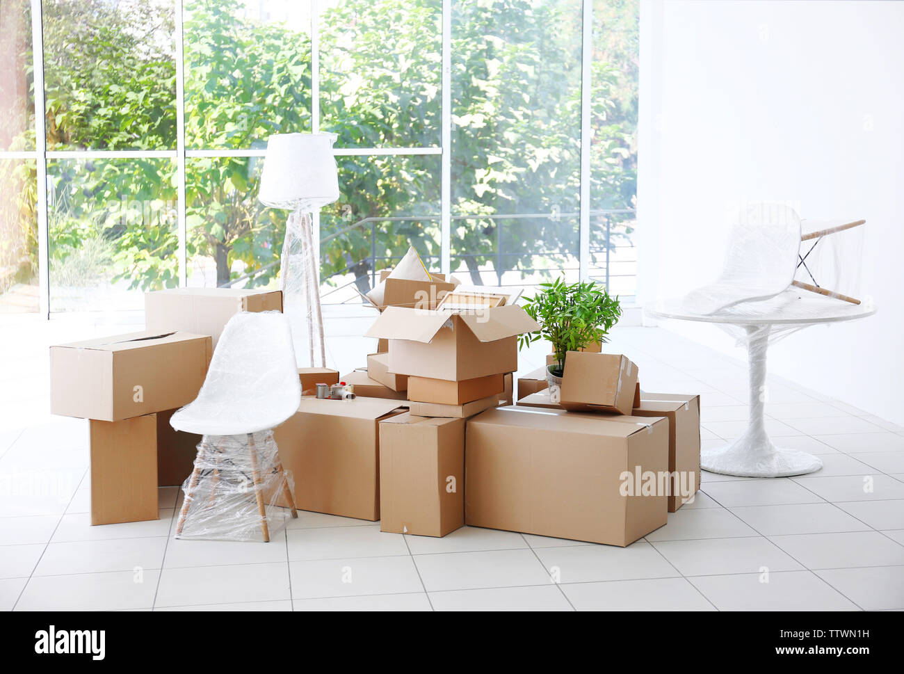 House moving concept. Boxes with furniture in new room with big window ...