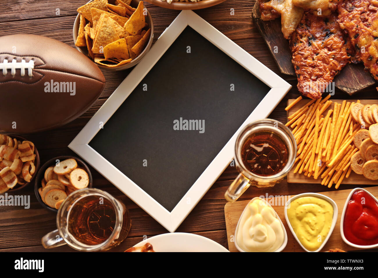 Rugby ball, frame and tasty snacks with beer on wooden table Stock ...