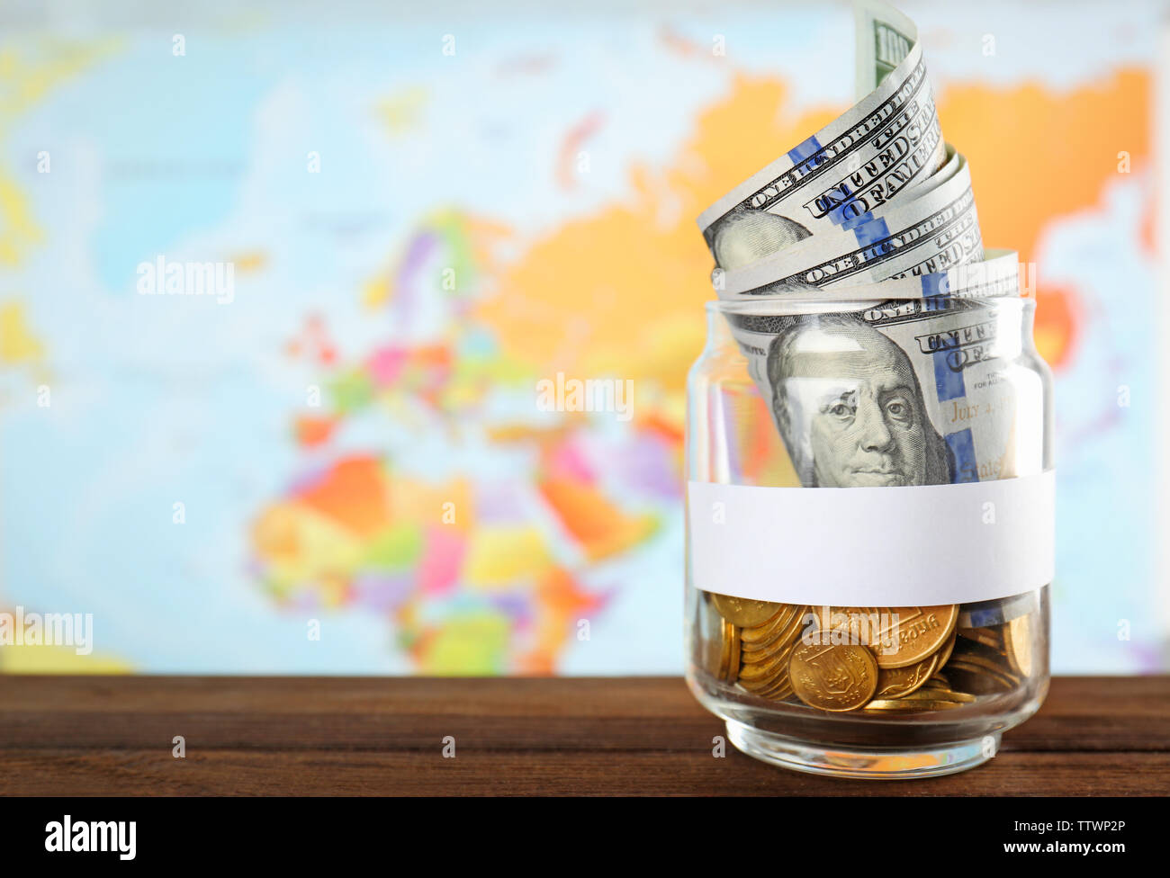 Glass jar with money on world map background Stock Photo - Alamy