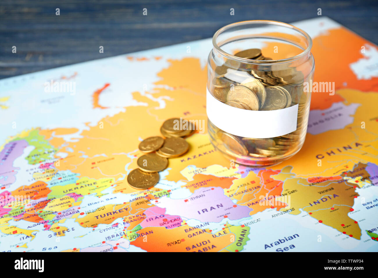 Glass jar with coins on world map Stock Photo - Alamy