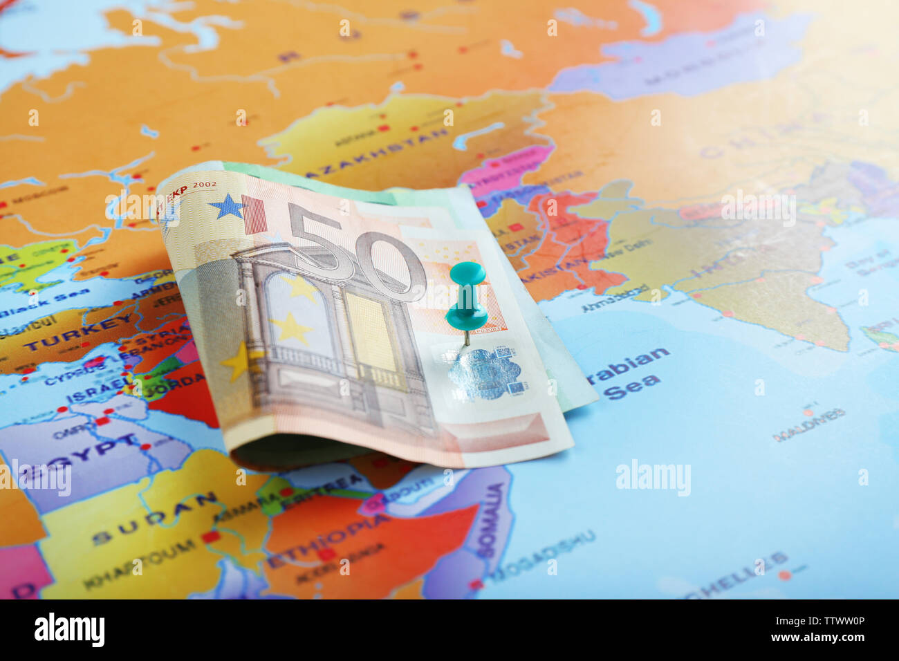 Euro banknotes fastened with push pin on world map background, closeup ...