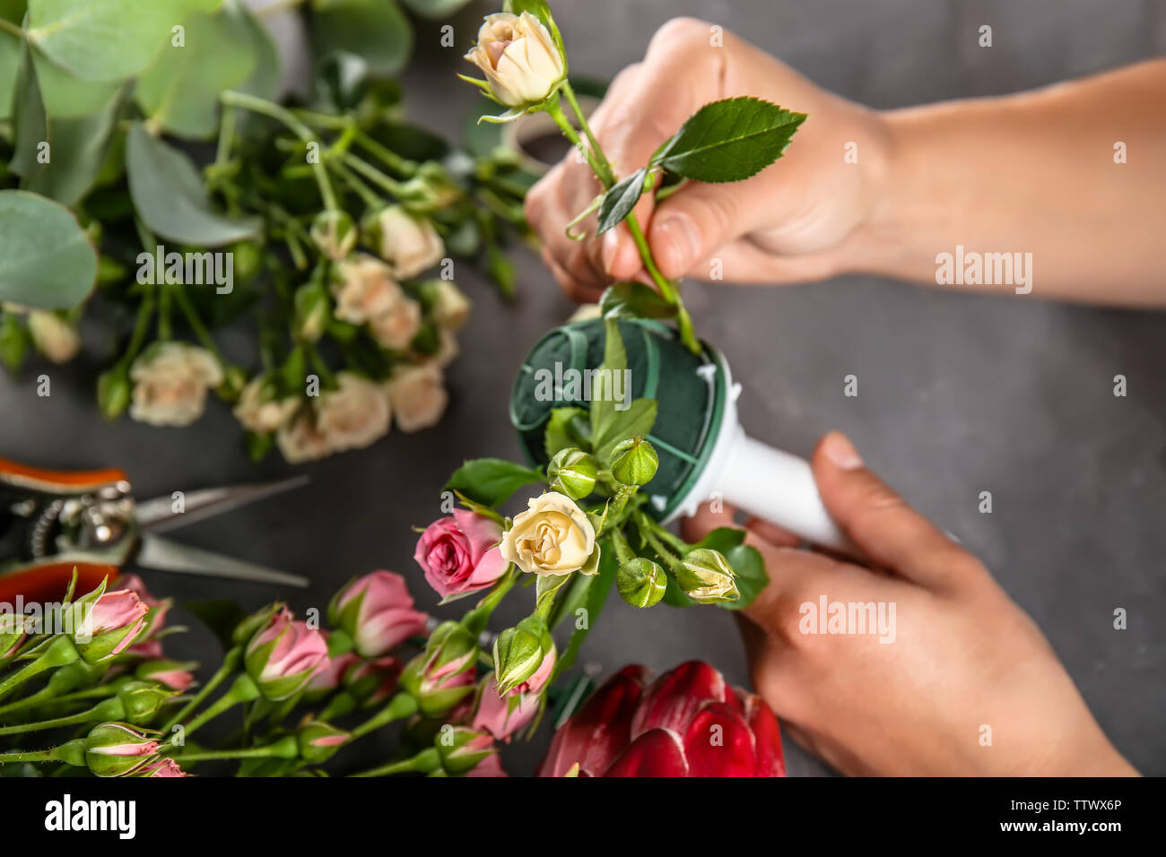 Female hands making beautiful bouquet of flowers on dark background ...