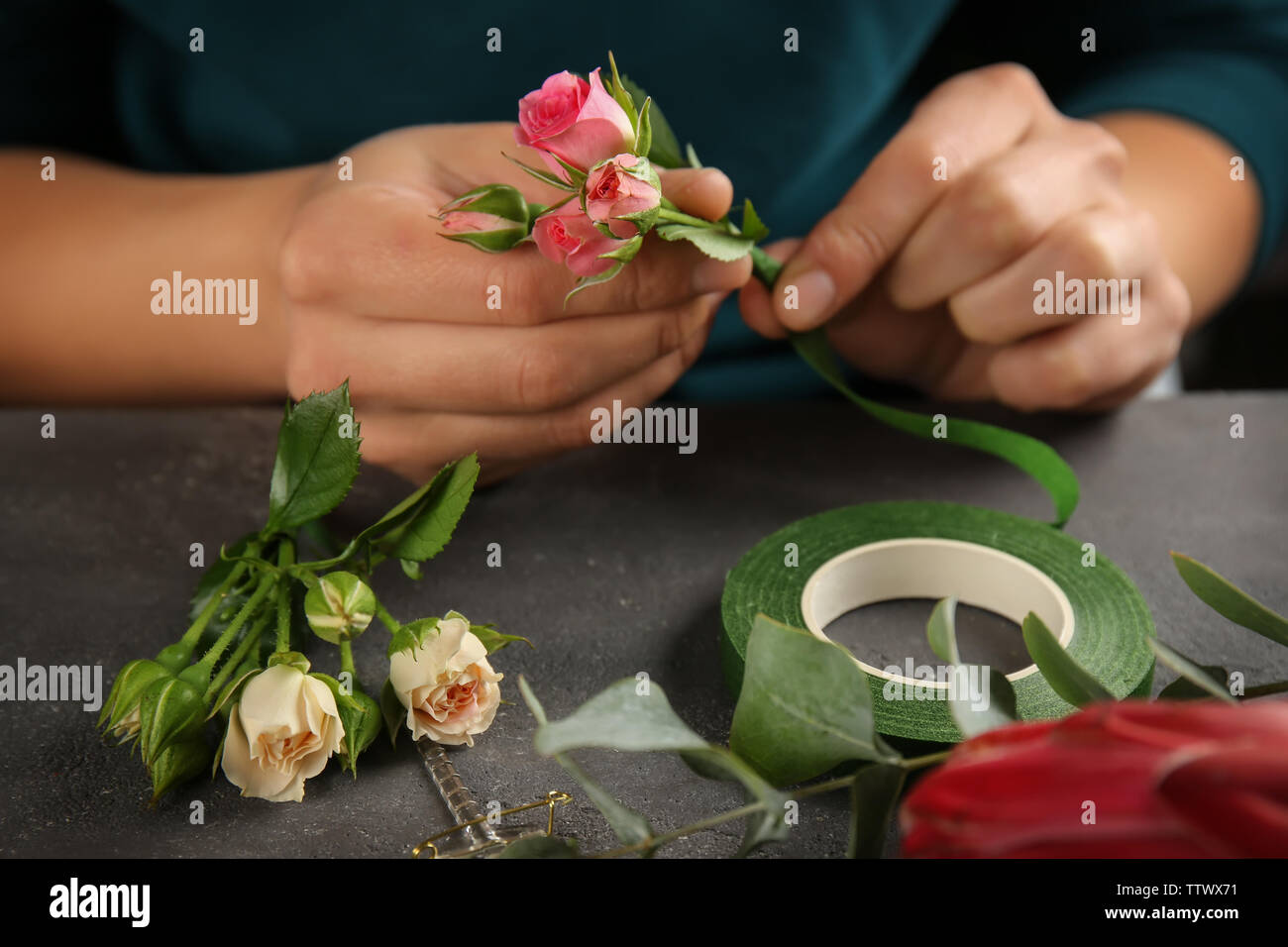 Female hands making beautiful bouquet of flowers on dark background ...