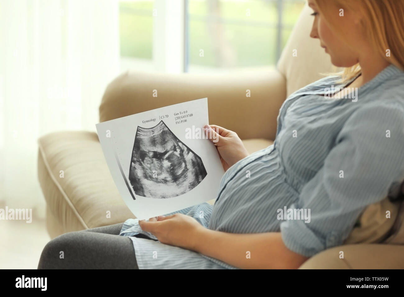 Pregnant woman with baby ultrasound scan sitting on couch at home Stock ...
