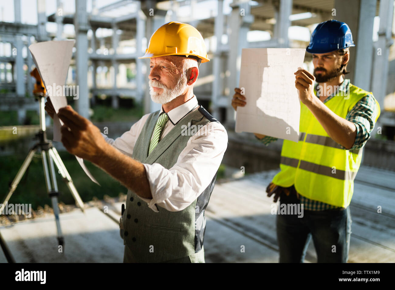 Engineer, foreman and worker discussing in building construction site ...