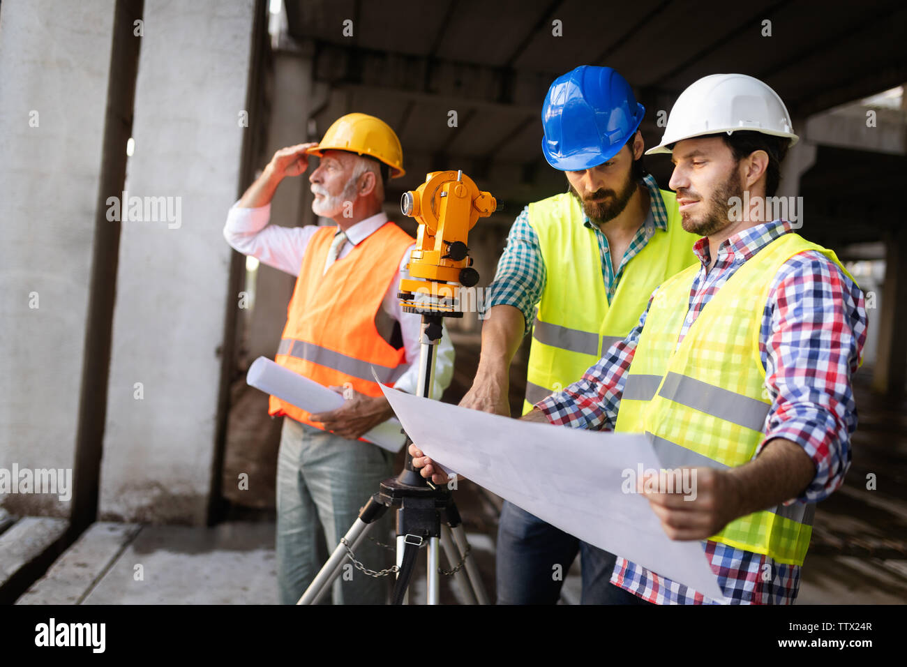 Engineer, foreman and worker discussing in building construction site ...