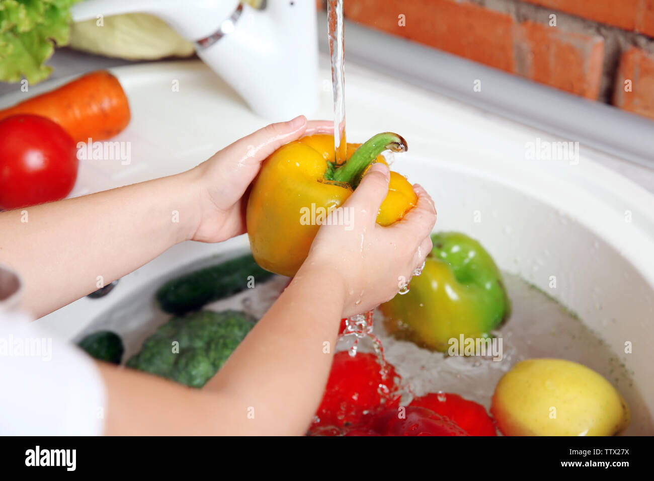 Small girl washing vegetables in kitchen Stock Photo - Alamy
