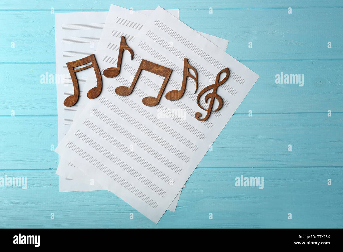Music notes and sheets of paper on color wooden background Stock Photo ...