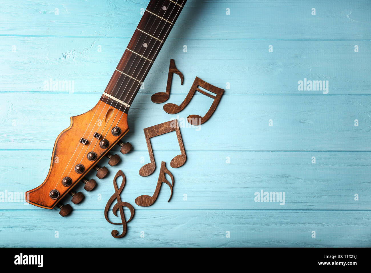 Guitar neck and music notes on color wooden background Stock Photo - Alamy