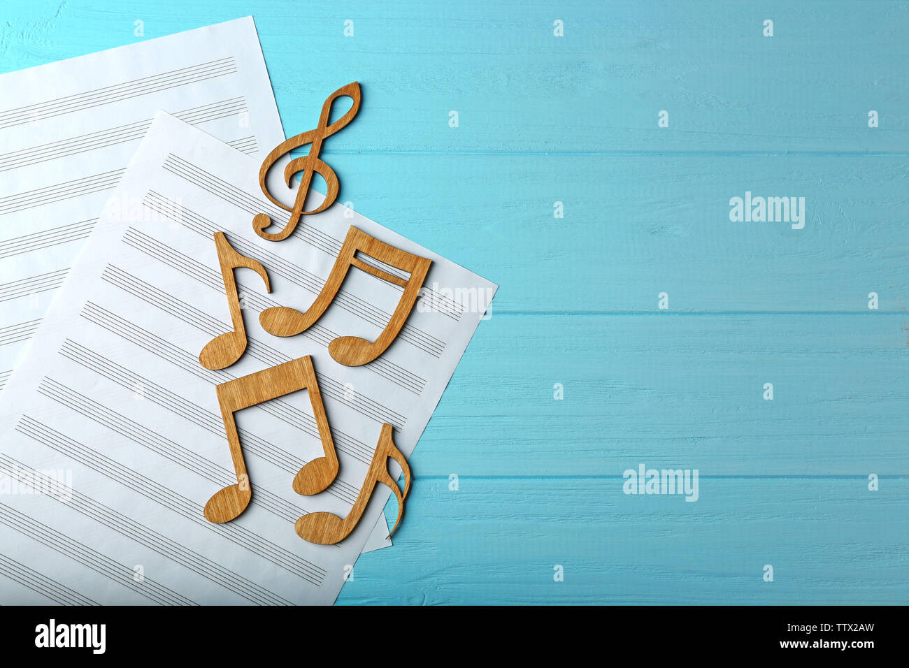 Music notes and sheets of paper on color wooden background Stock Photo ...