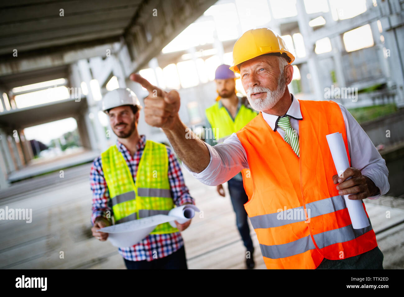 Engineer, foreman and worker discussing in building construction site ...