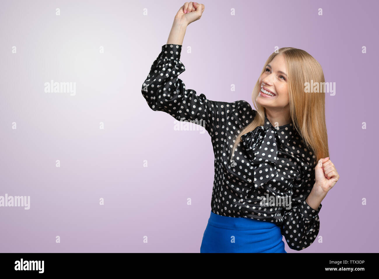 Pretty young blonde woman throwing her arms up into the air in ...