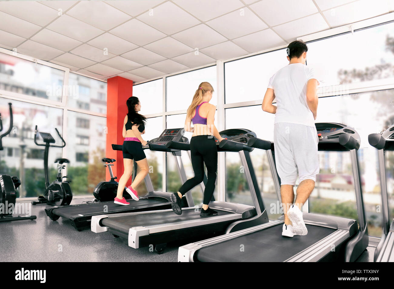 Young people running on treadmills in gym Stock Photo - Alamy
