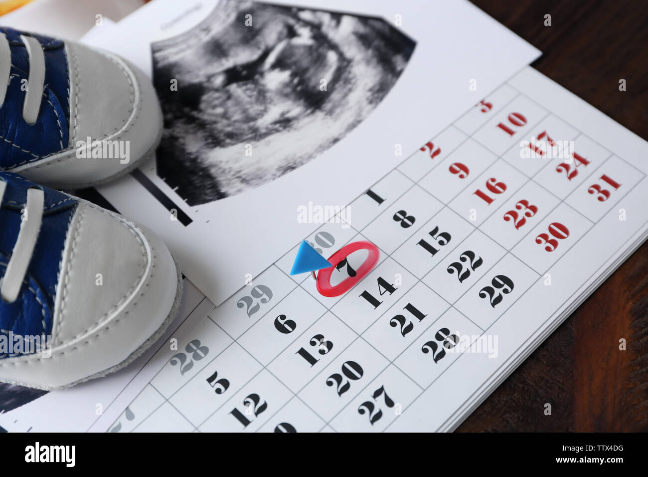 Calendar with ultrasound scan of baby and children shoes, closeup Stock ...